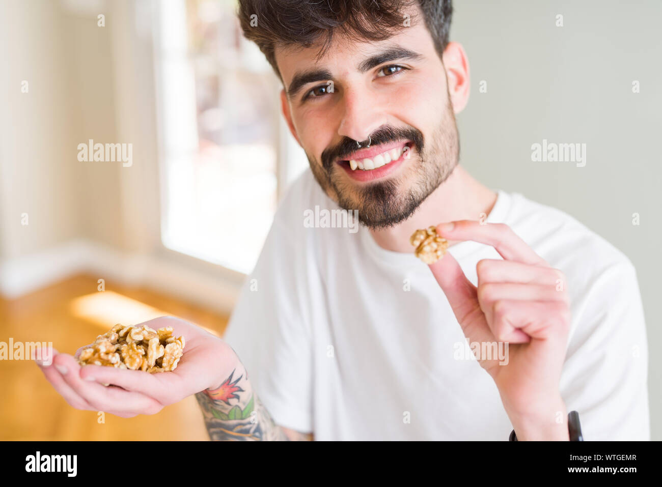 Young man eating walnuts, close up of hand with a bunch of healthy nuts ...