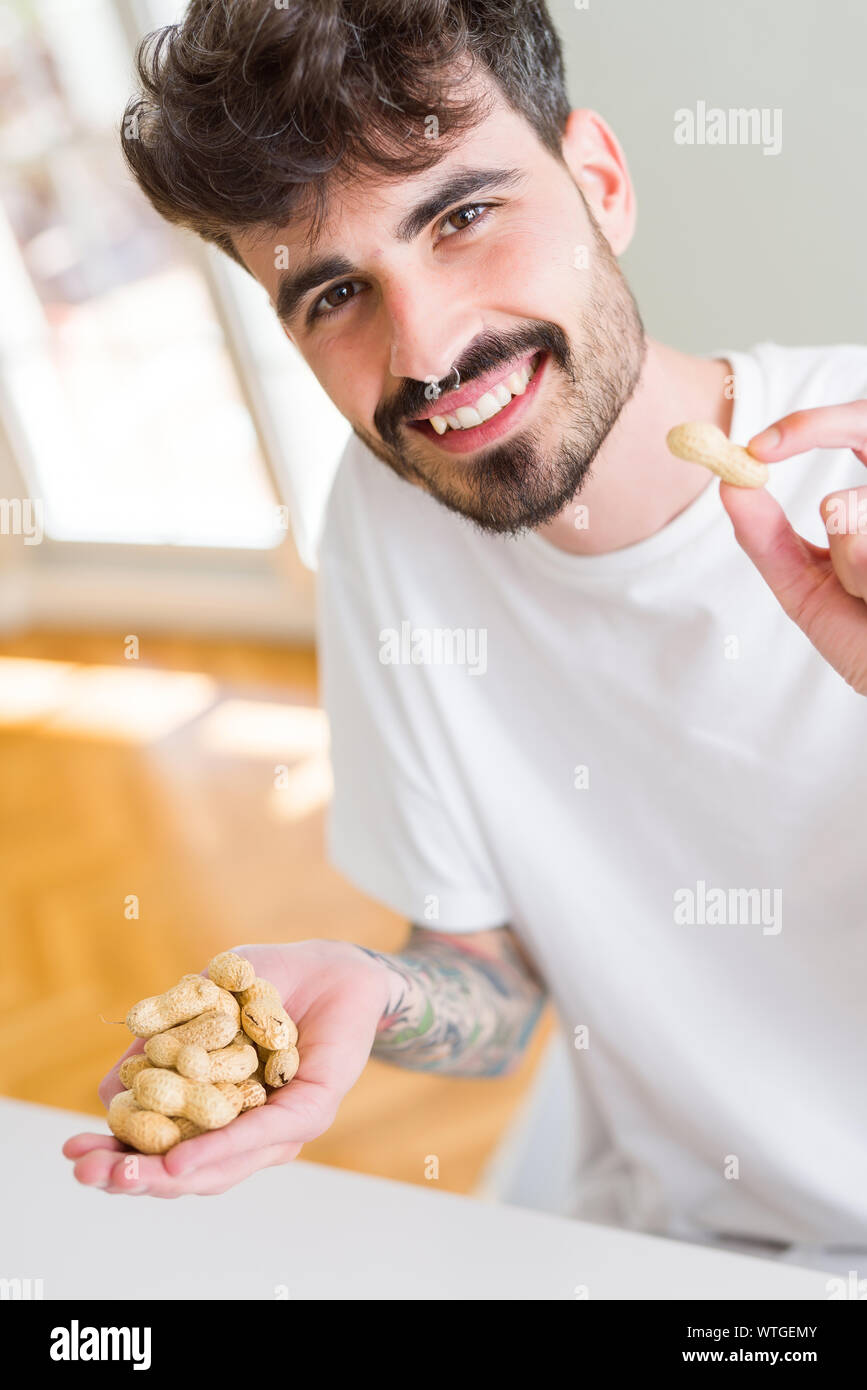 Young man eating peanuts, close up of hand with a bunch of healthy nuts ...