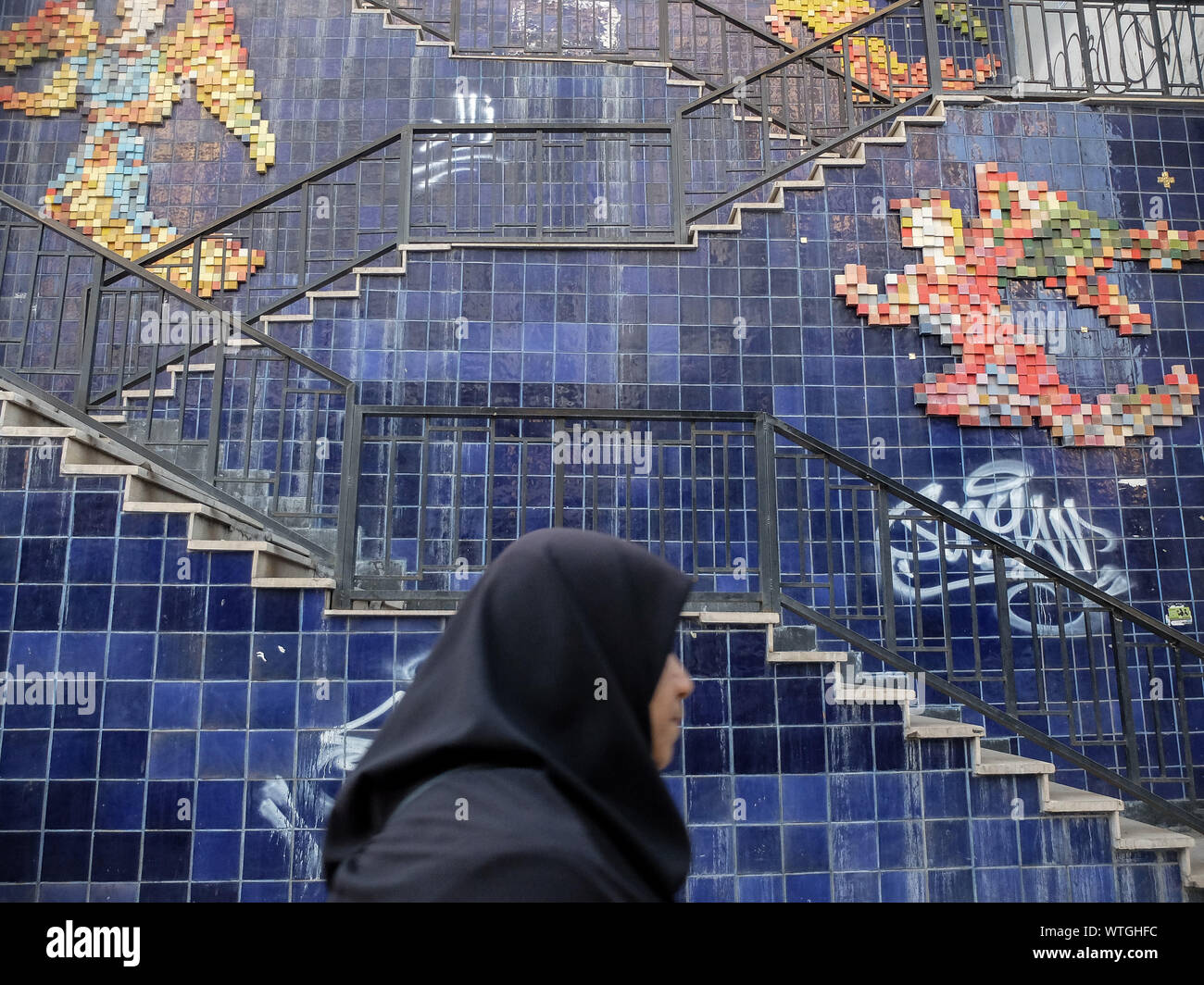 Tehran, Iran. 12th Sep, 2019. A veiled woman walks past a mural in a ...