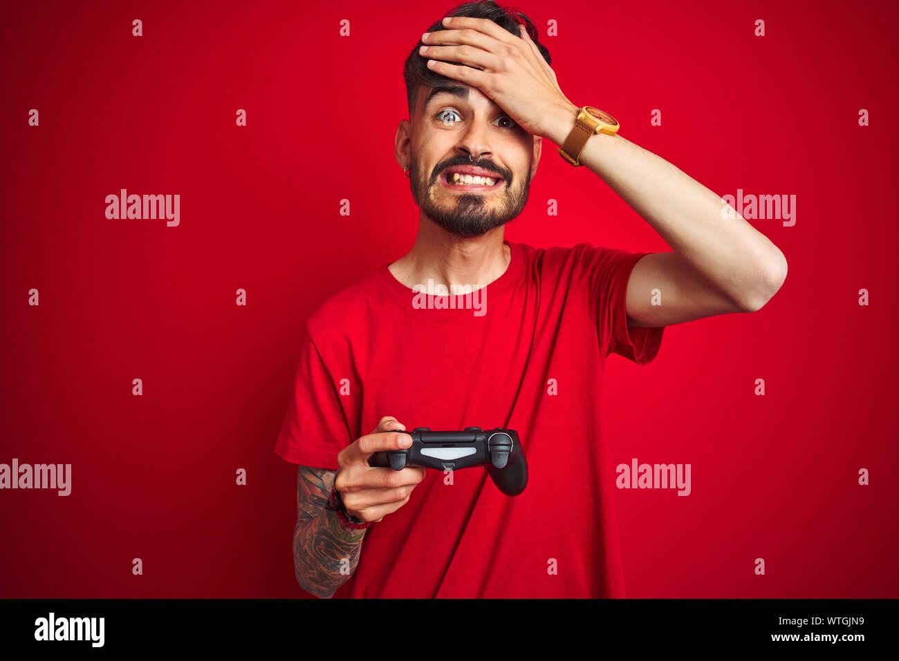 Young gamer man with tattoo playing video game standing over isolated ...