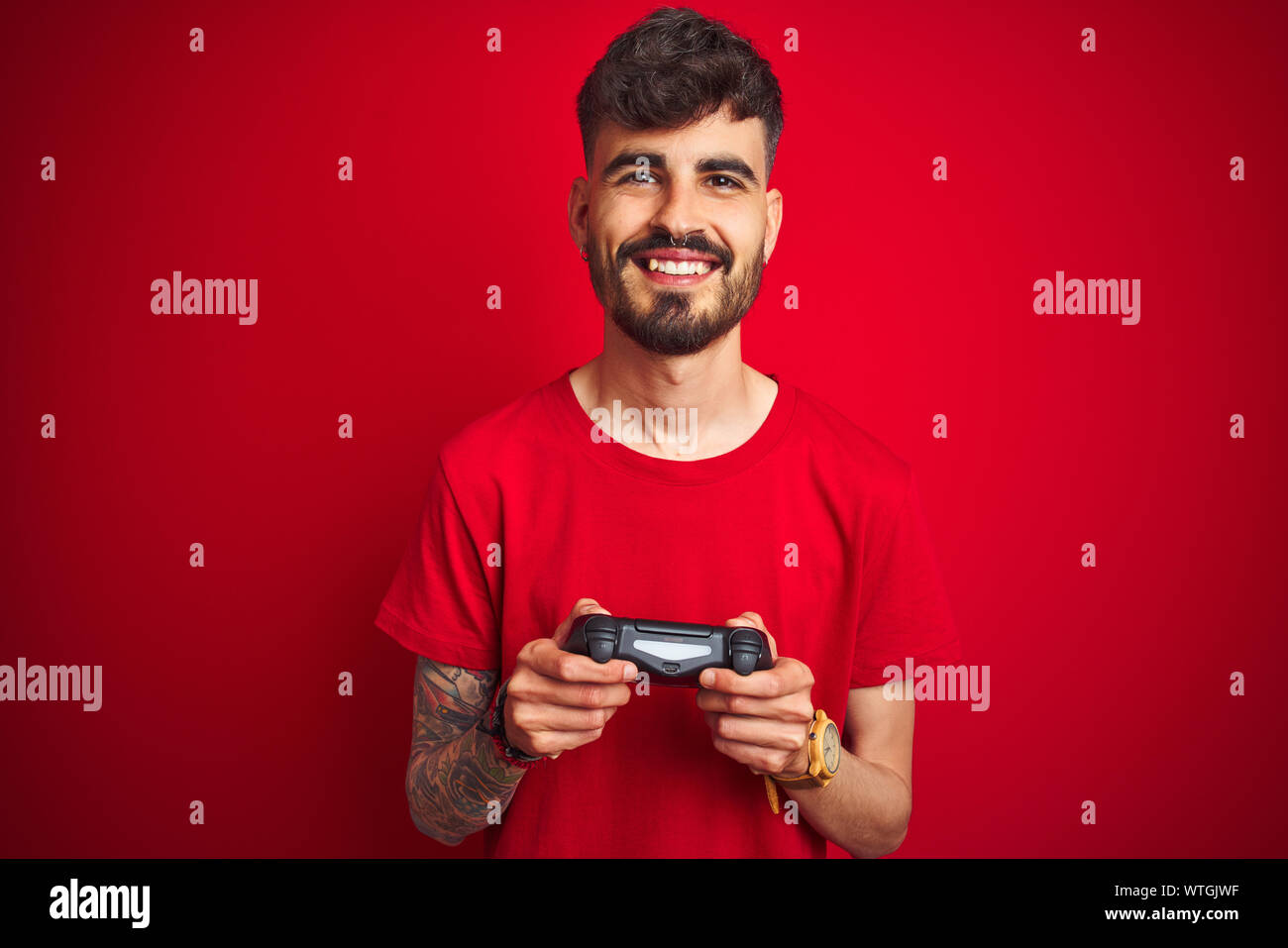 Young gamer man with tattoo playing video game standing over isolated ...