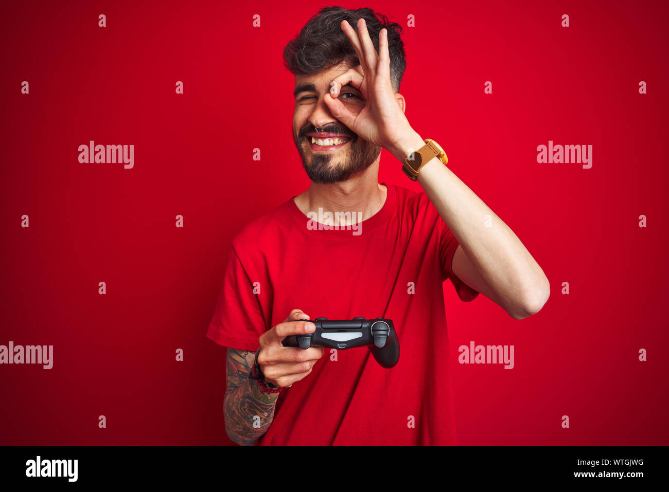 Young gamer man with tattoo playing video game standing over isolated ...
