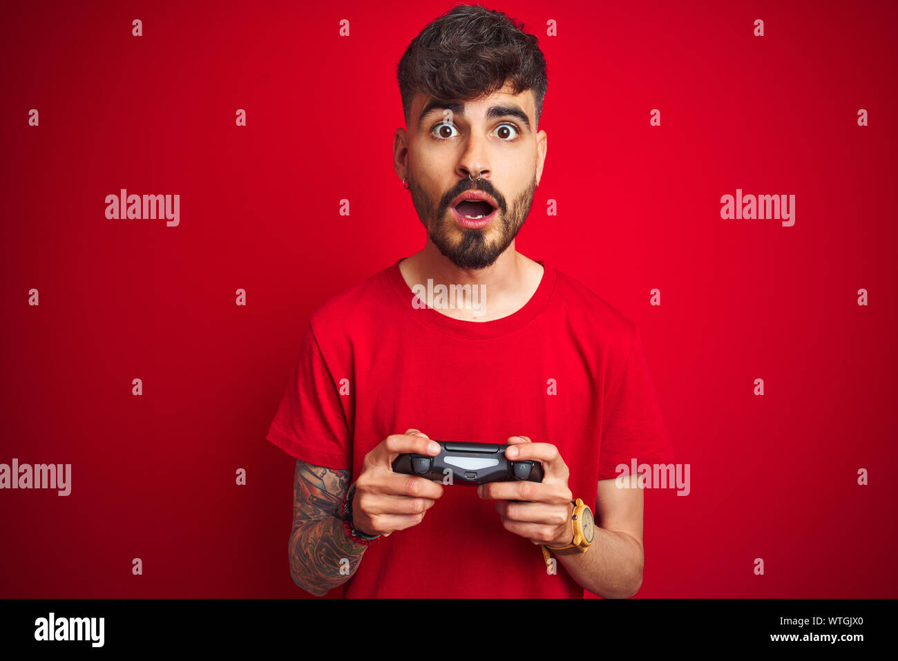 Young gamer man with tattoo playing video game standing over isolated ...