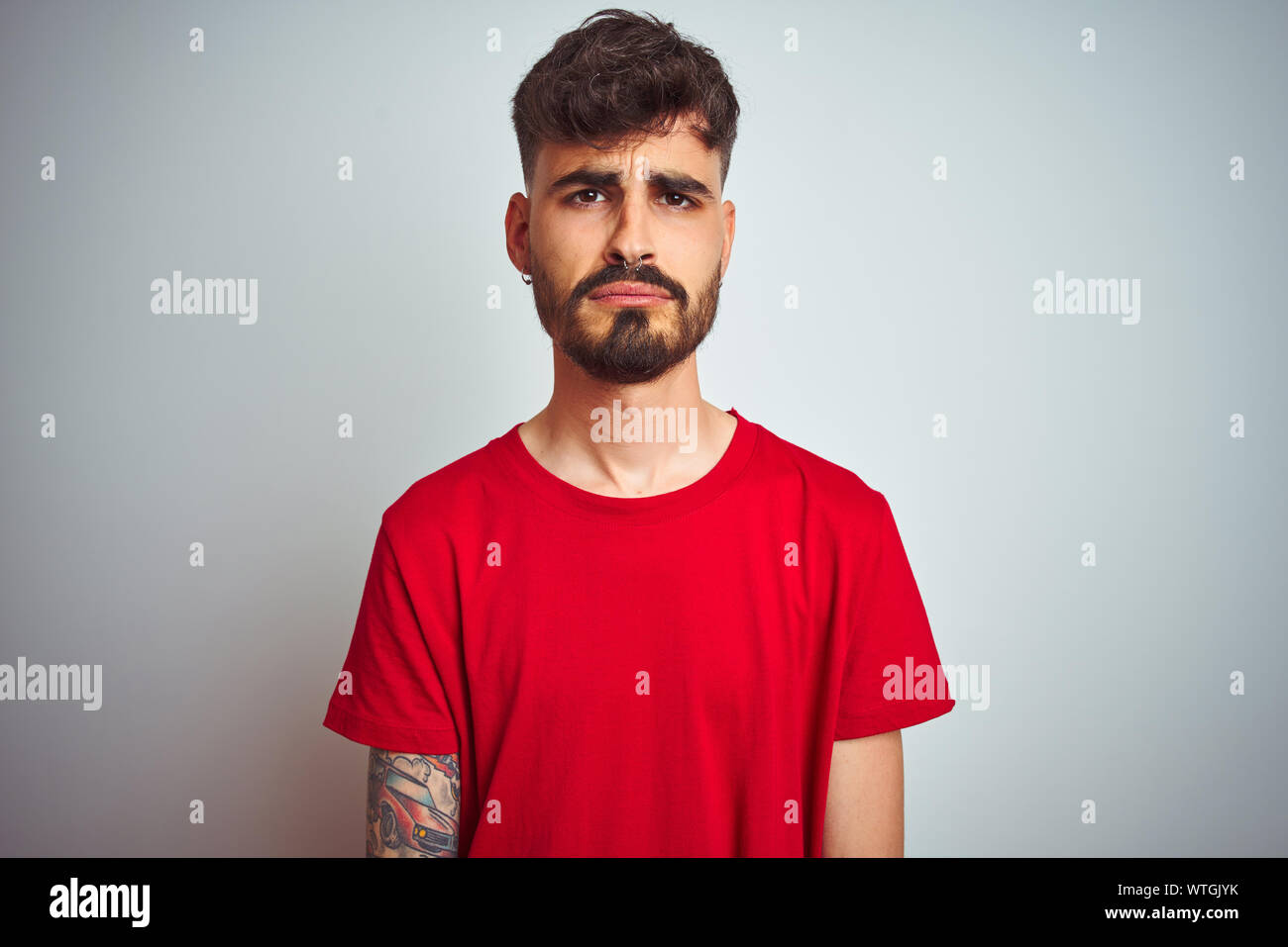 Young man with tattoo wearing red t-shirt standing over isolated white ...