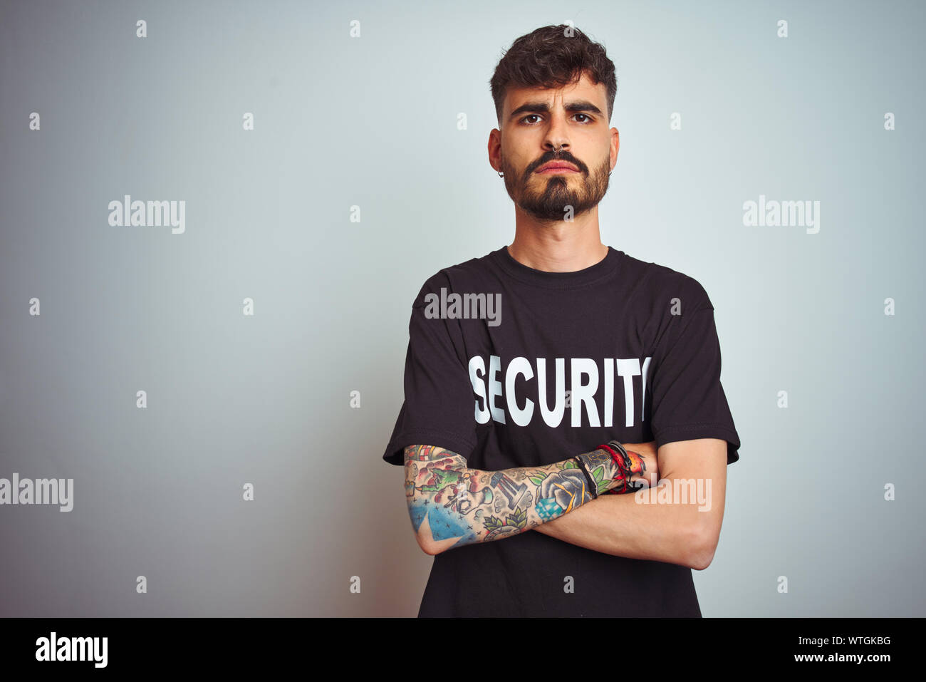 Young safeguard man with tattoo wering security uniform over isolated ...