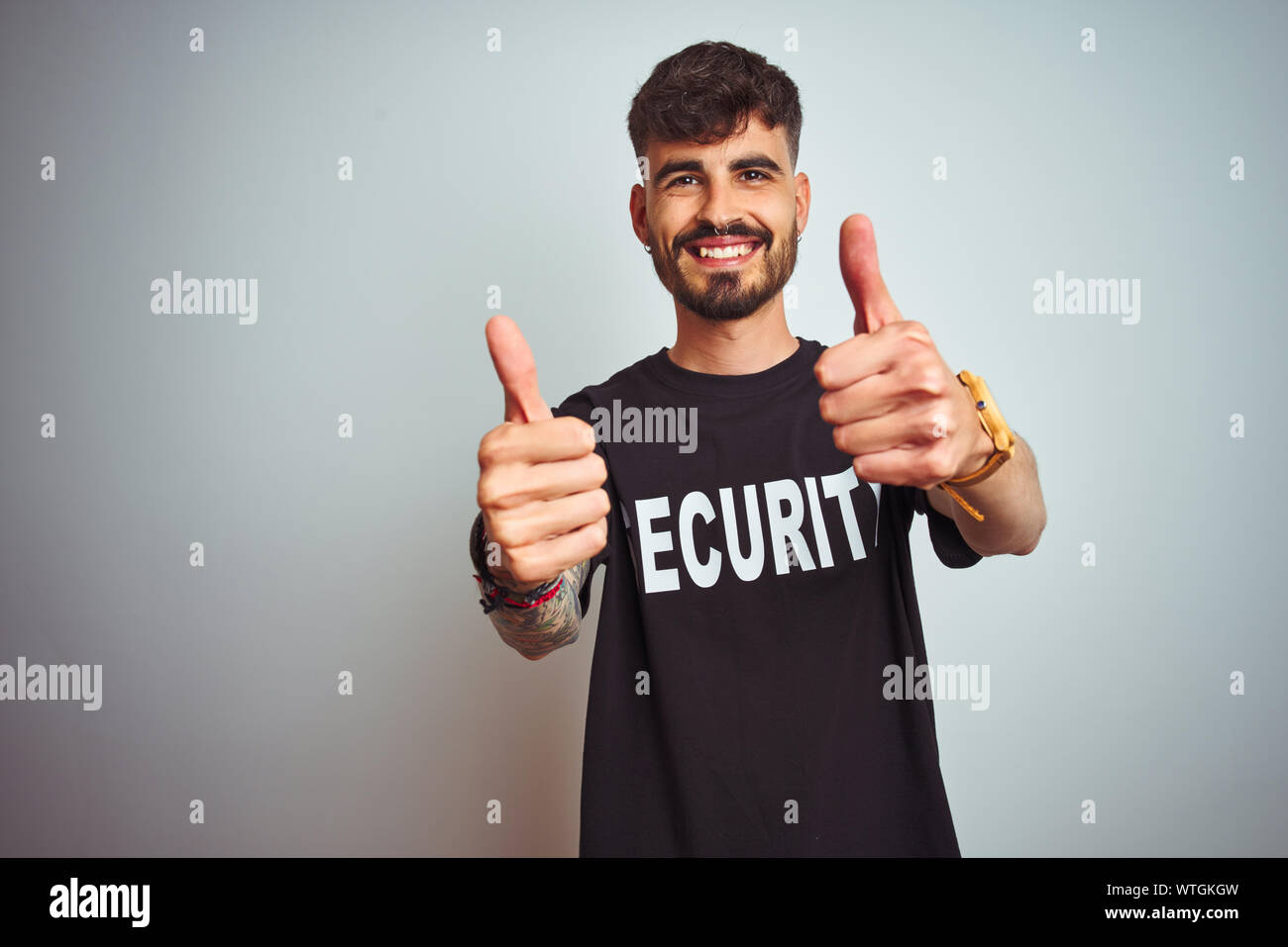 Young safeguard man with tattoo wering security uniform over isolated ...
