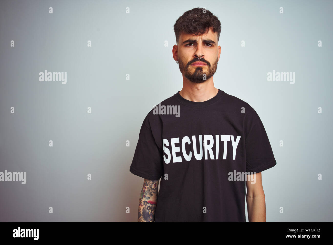 Young safeguard man with tattoo wering security uniform over isolated ...