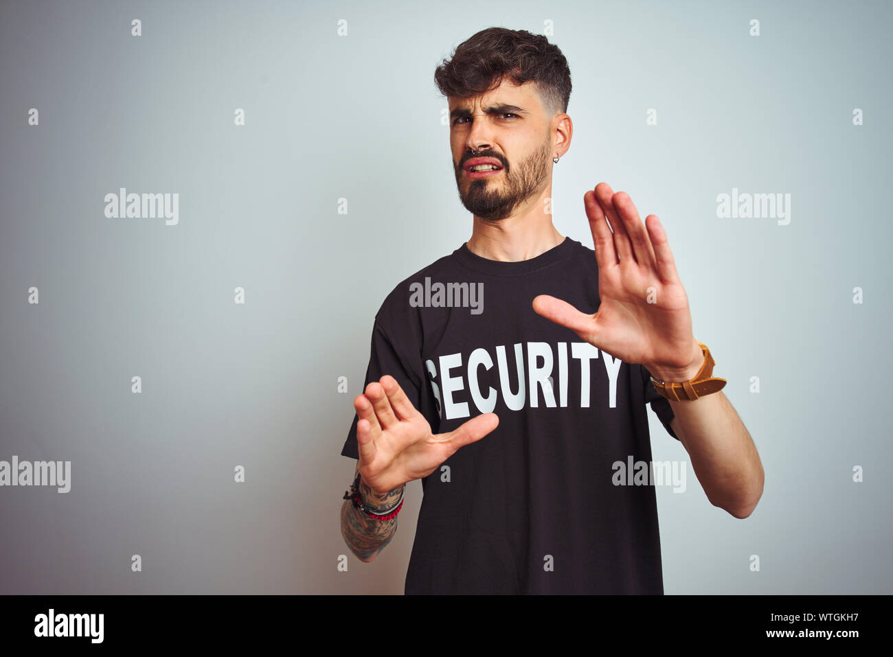 Young safeguard man with tattoo wering security uniform over isolated ...