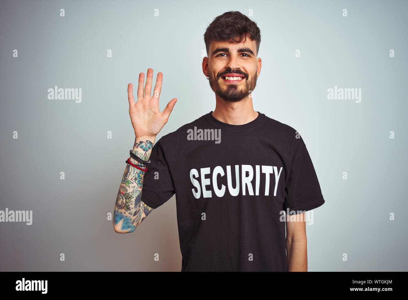 Young safeguard man with tattoo wering security uniform over isolated ...