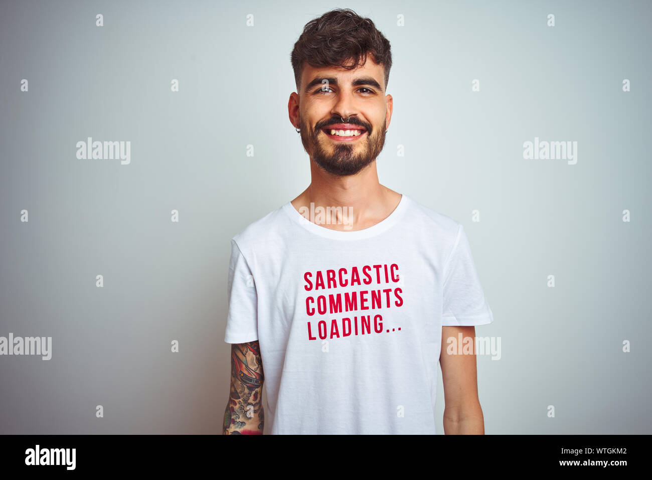 Young man with tattoo wearing fanny t-shirt standing over isolated ...