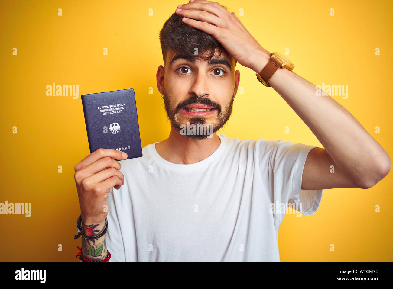 Young man with tattoo wearing German Germany passport over isolated ...