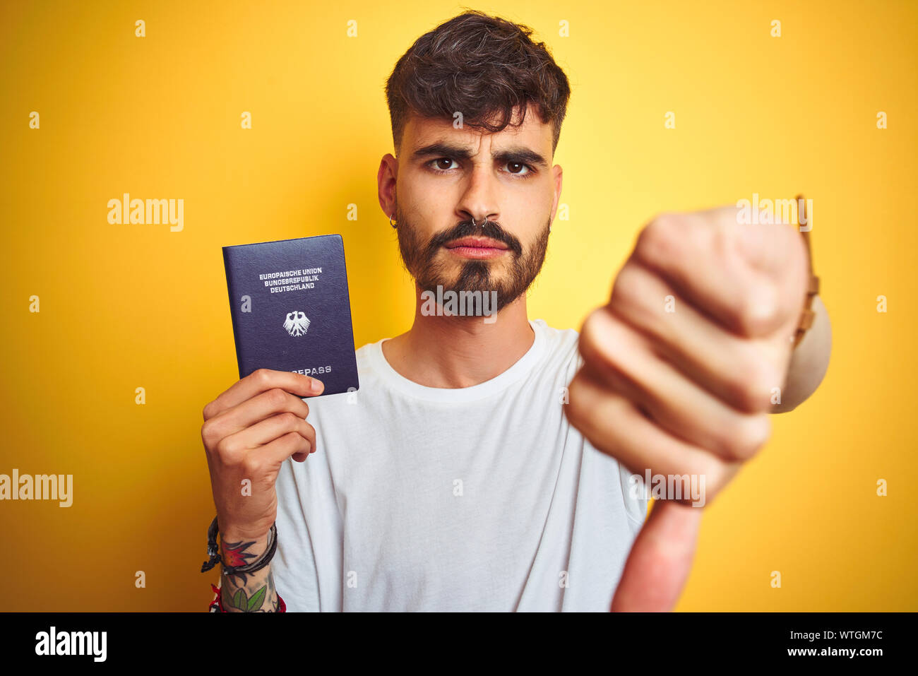 Young man with tattoo wearing German Germany passport over isolated ...