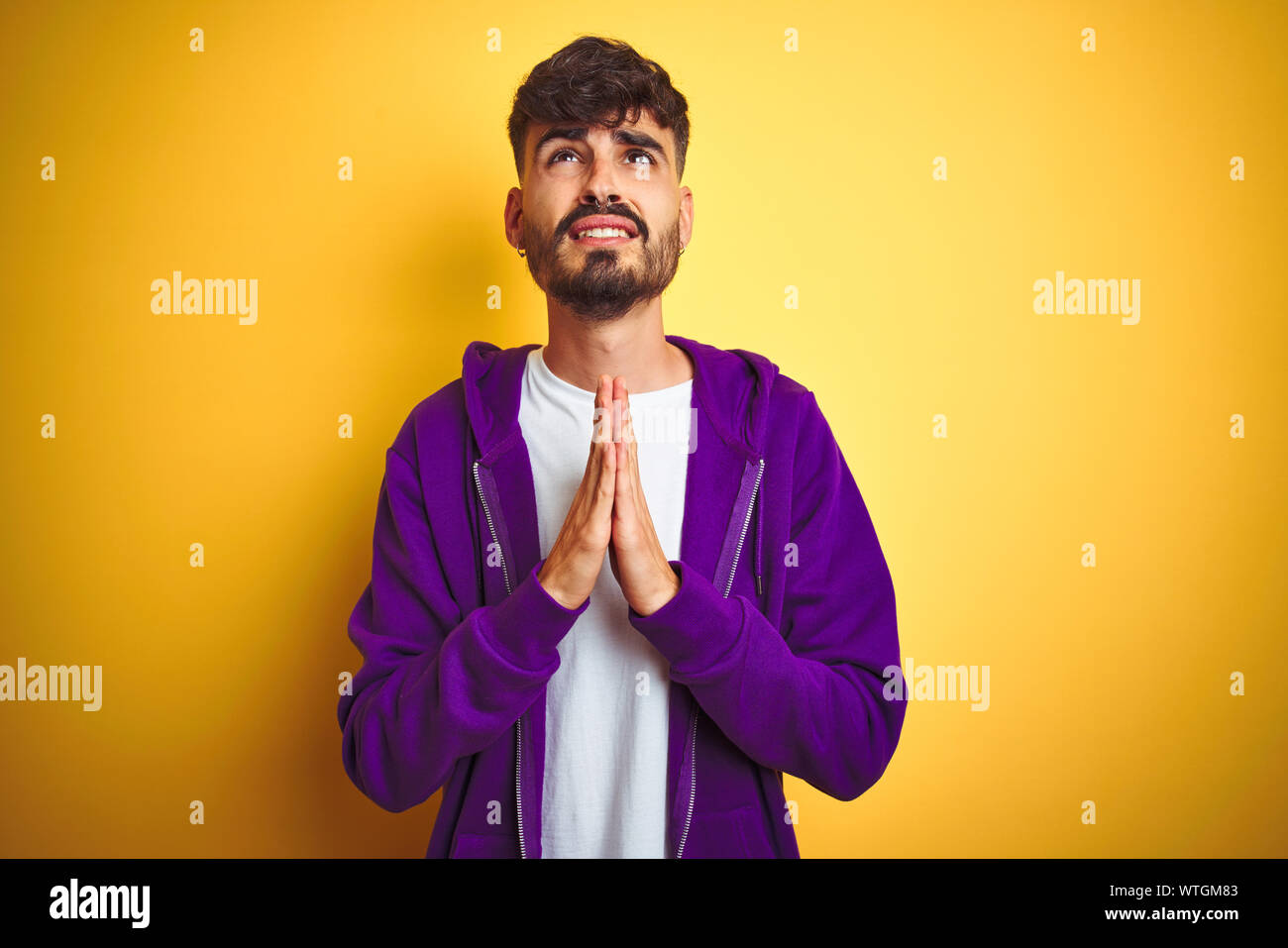 Young man with tattoo wearing sport purple sweatshirt over isolated ...