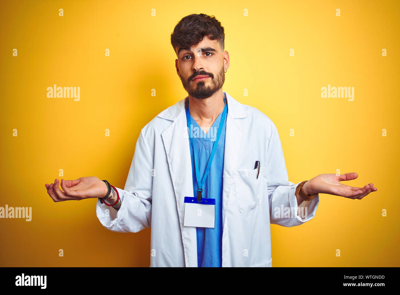 Young doctor man with tattoo wearing id card standing over isolated ...