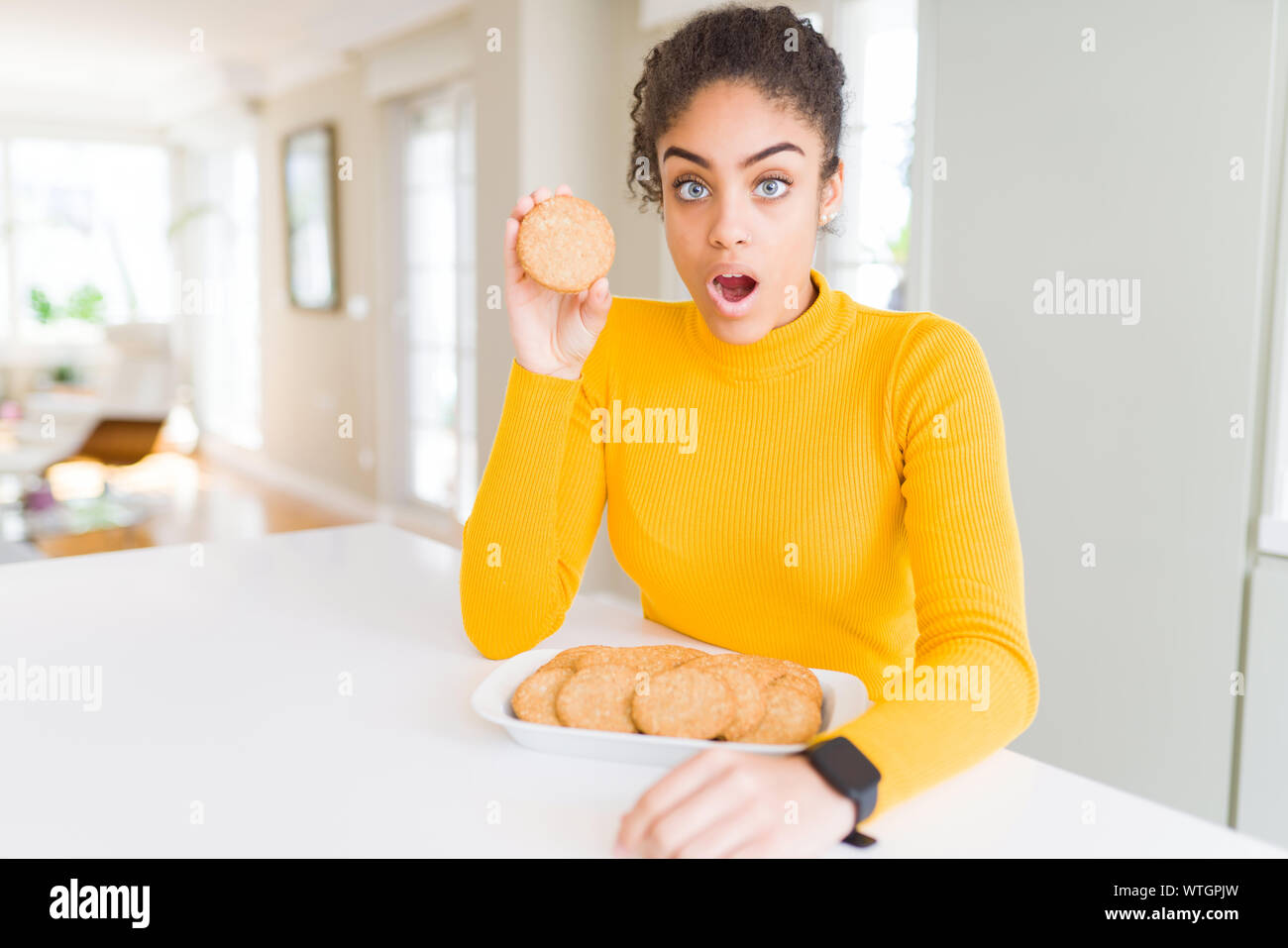 Young african american girl eating healthy whole grain biscuits scared ...