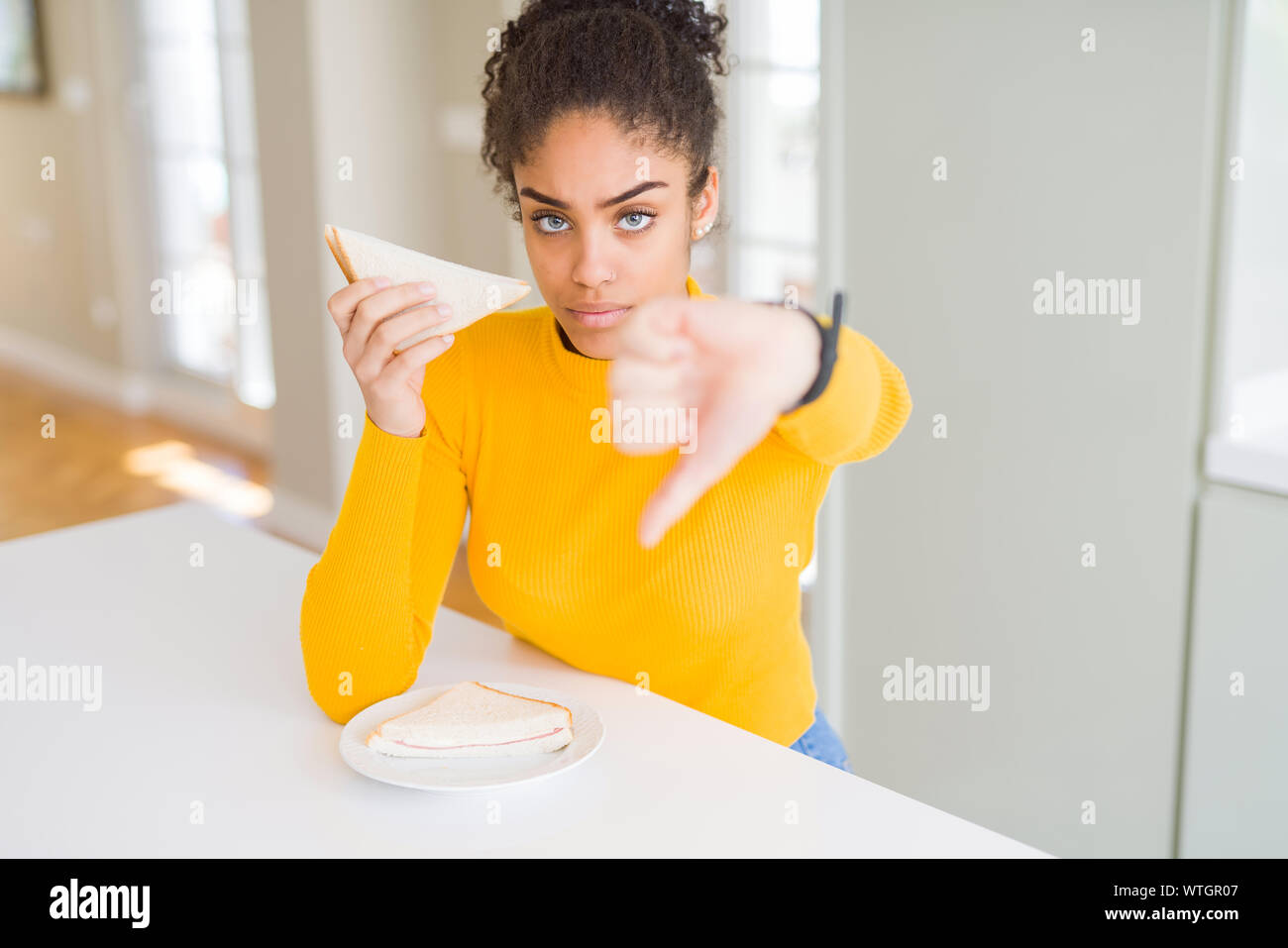 Young african american woman eating a sandwich as healthy snack with ...