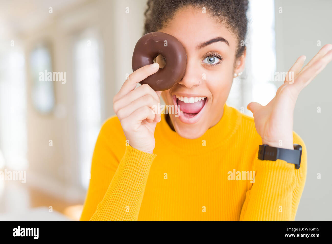 Young african american girl eating sweet chocolate donut very happy and ...
