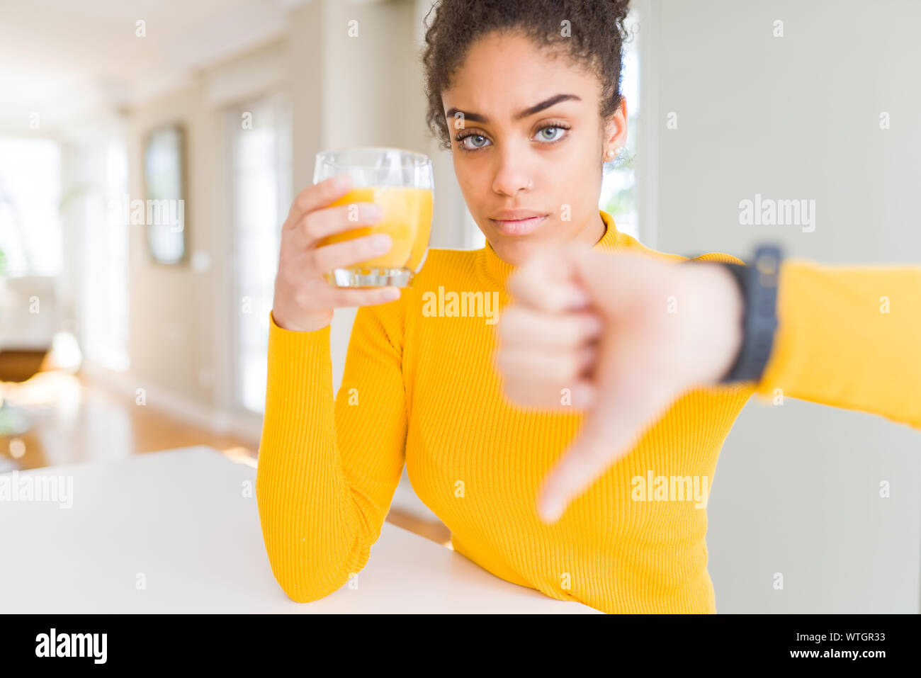 Young african american woman drinking a glass of fresh orange juice ...