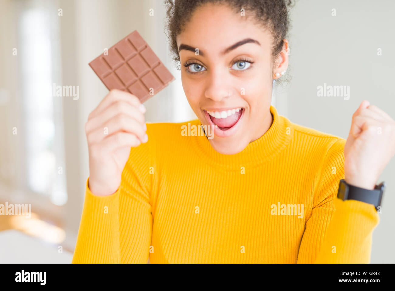 Young african american girl eating dark chocolate bar as a sweet snack ...