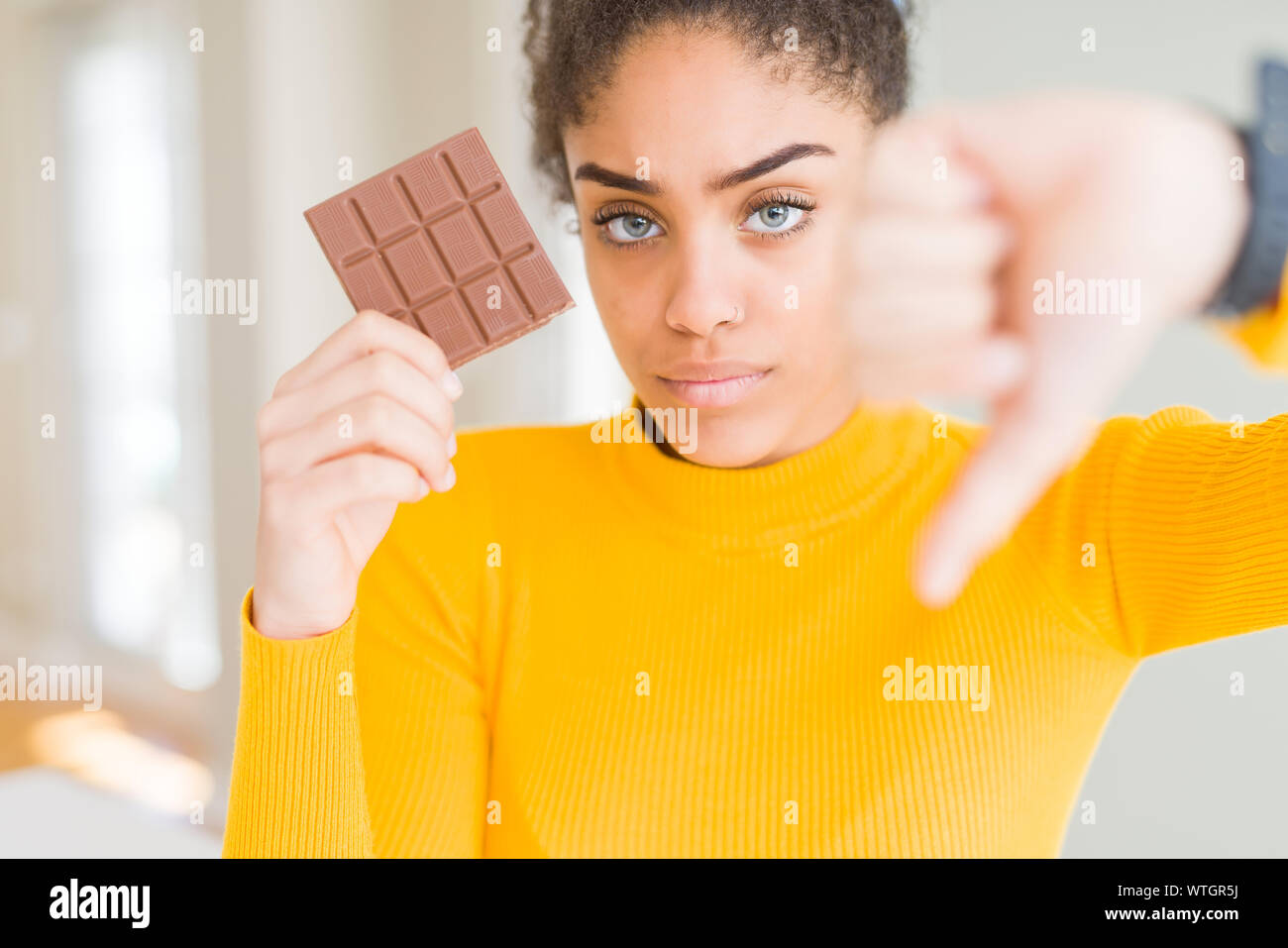 Young african american girl eating dark chocolate bar as a sweet snack ...