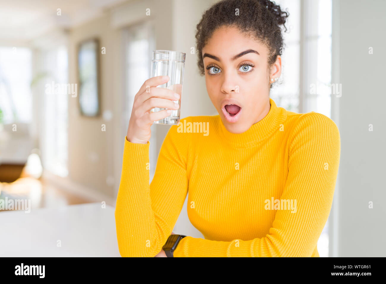 Young african american woman drinking a glass of fresh water scared in ...