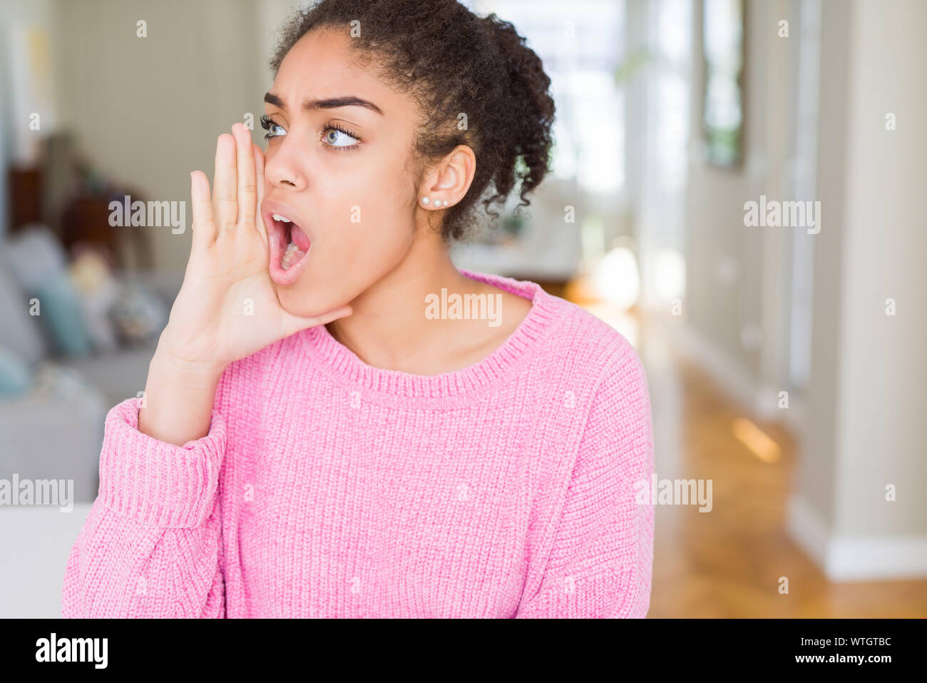 Beautiful young african american woman with afro hair shouting and ...
