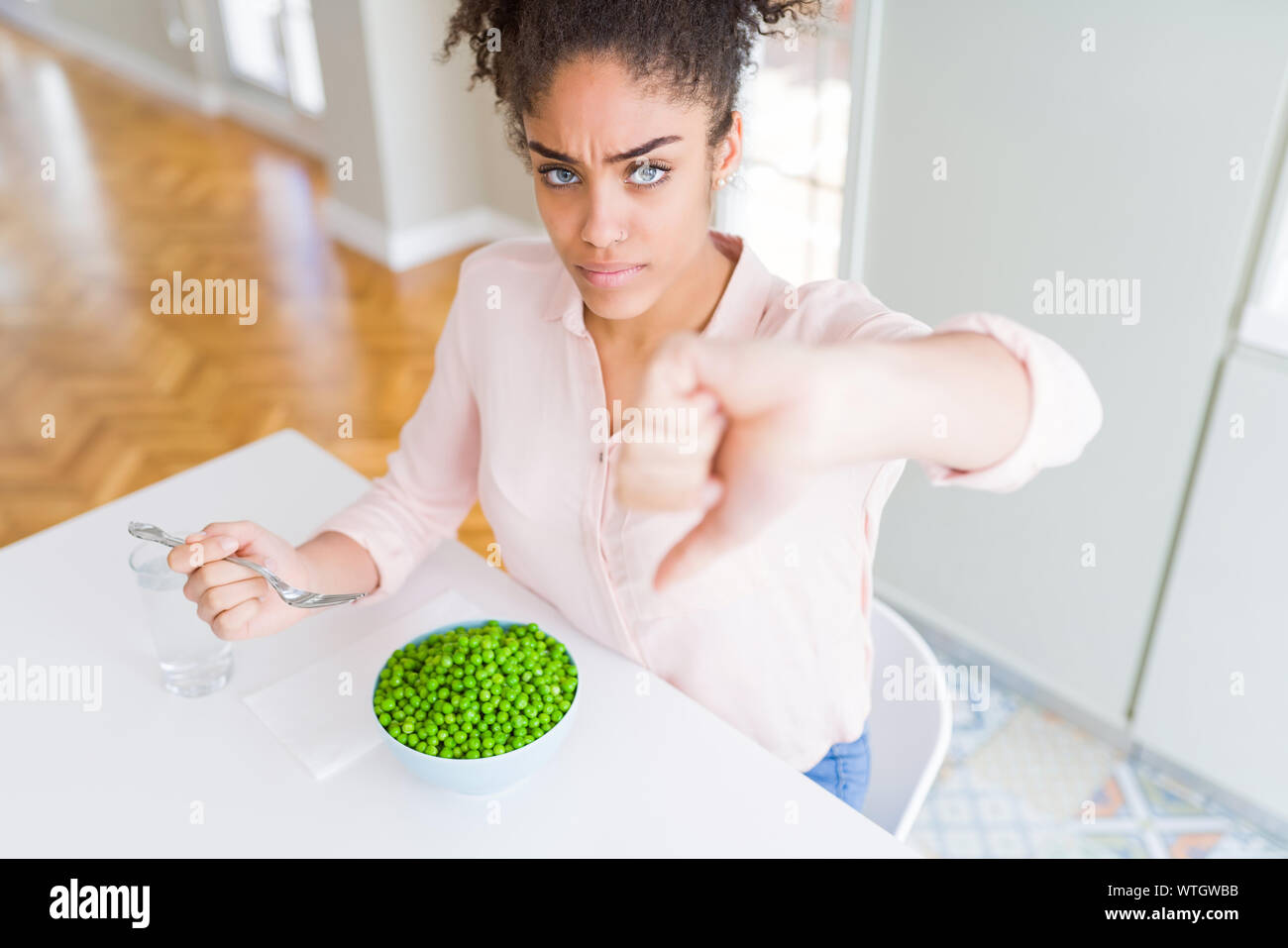 Young african american girl eating healthy green peas with angry face ...