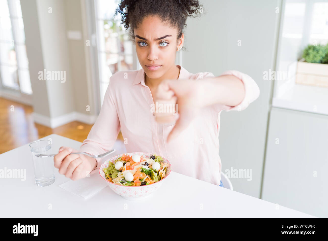Young african american woman eating healthy pasta salad with angry face ...