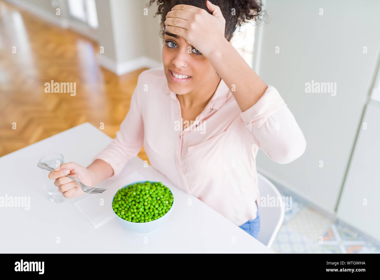 Young african american girl eating healthy green peas stressed with ...