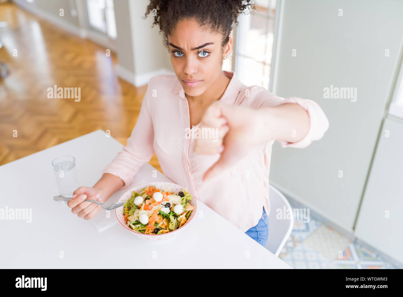 Young african american woman eating healthy pasta salad with angry face ...