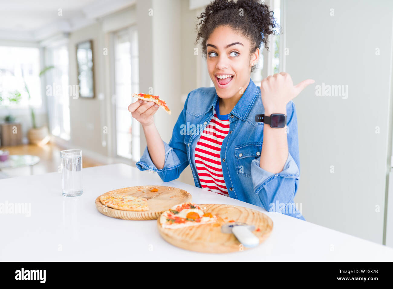 Young african american woman eating two homemade cheese pizzas pointing ...