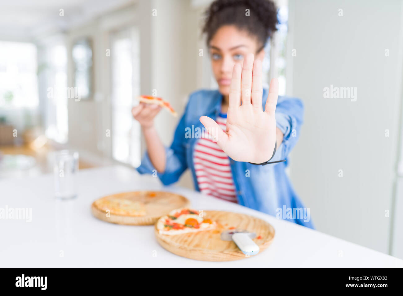 Young african american woman eating two homemade cheese pizzas with ...