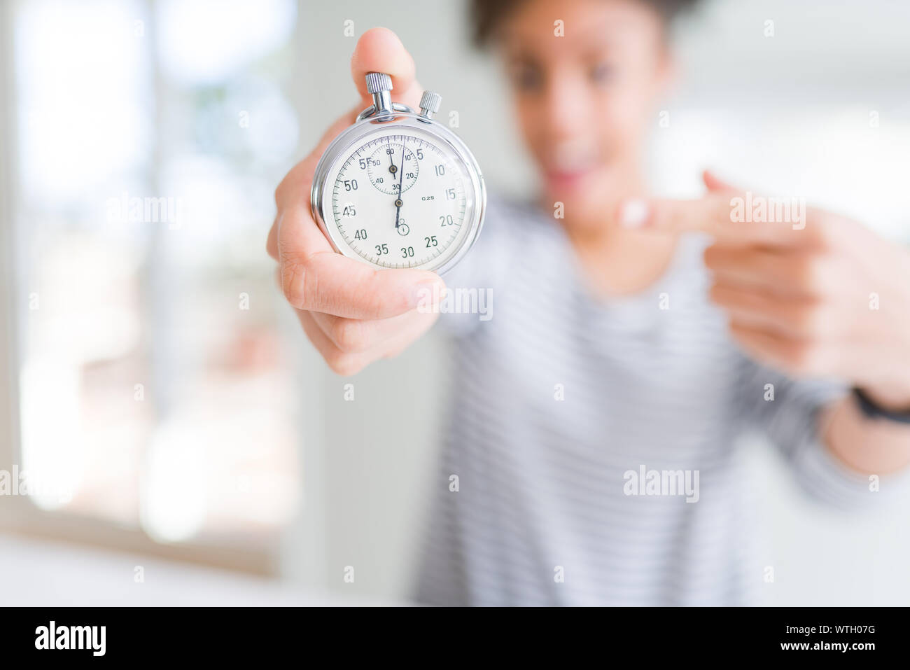 Young african american woman holding stopwatch very happy pointing with ...