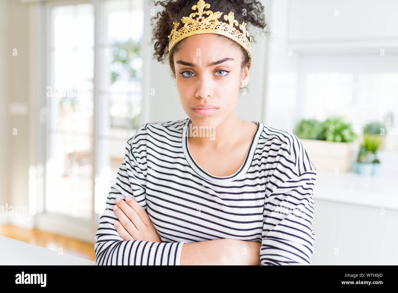 Young african american girl wearing golden queen crown on head skeptic ...