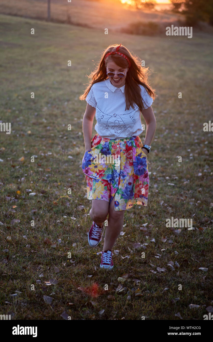 Fashionable girl running through the field at sunset Stock Photo - Alamy