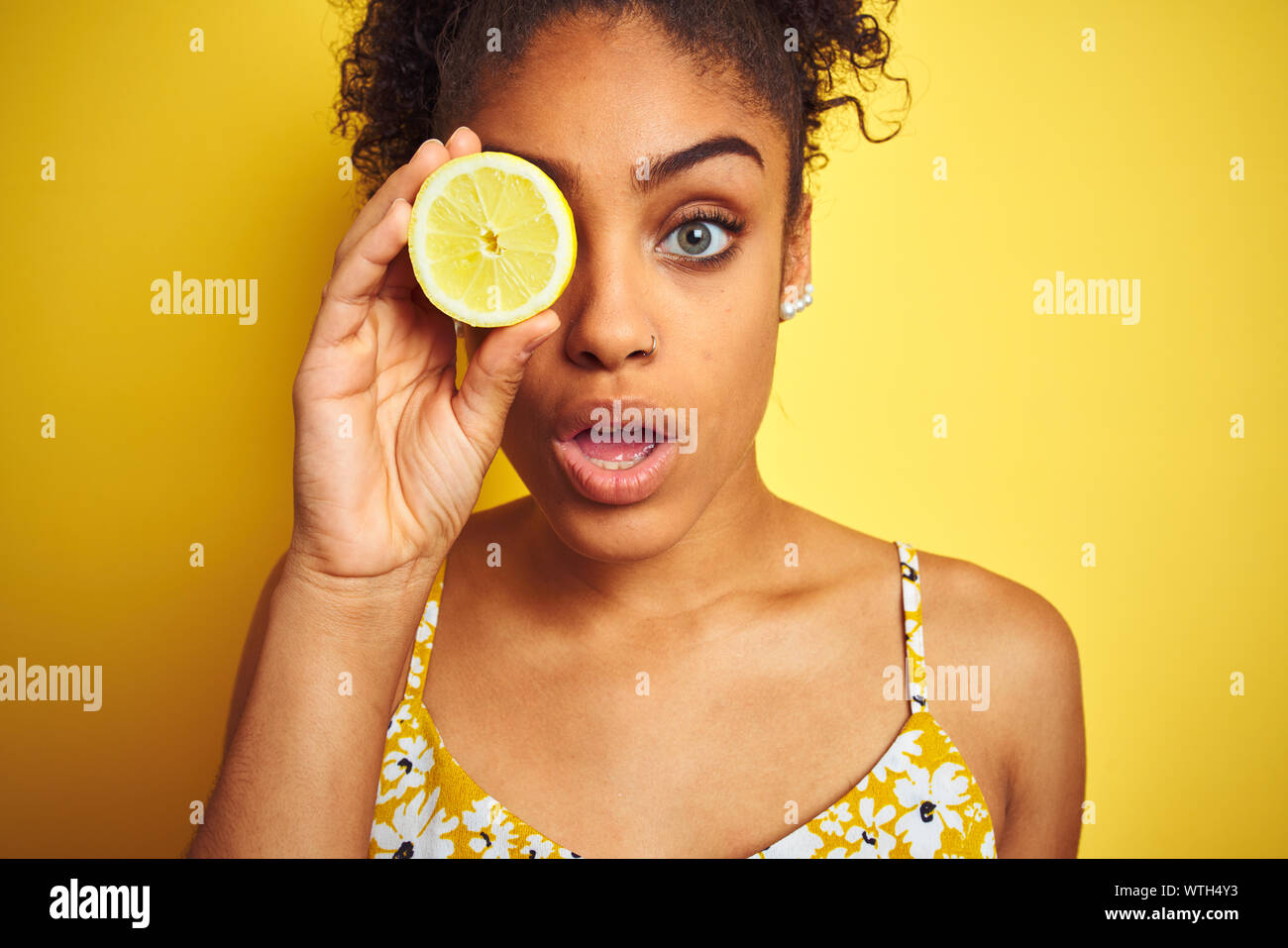 Young african american woman holding slice of lemon over isolated ...