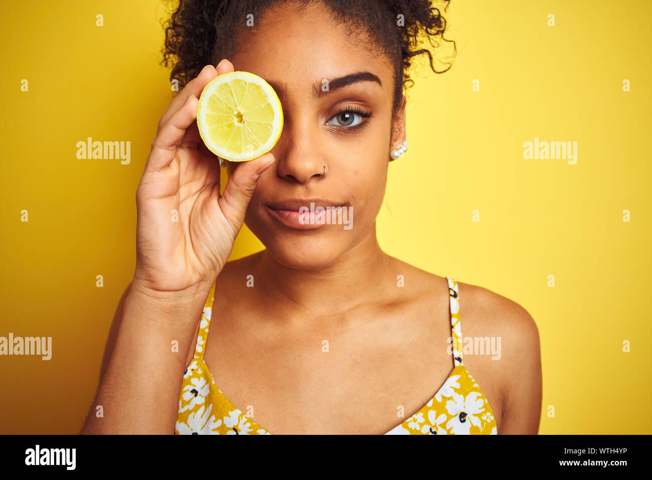 Young african american woman holding slice of lemon over isolated ...
