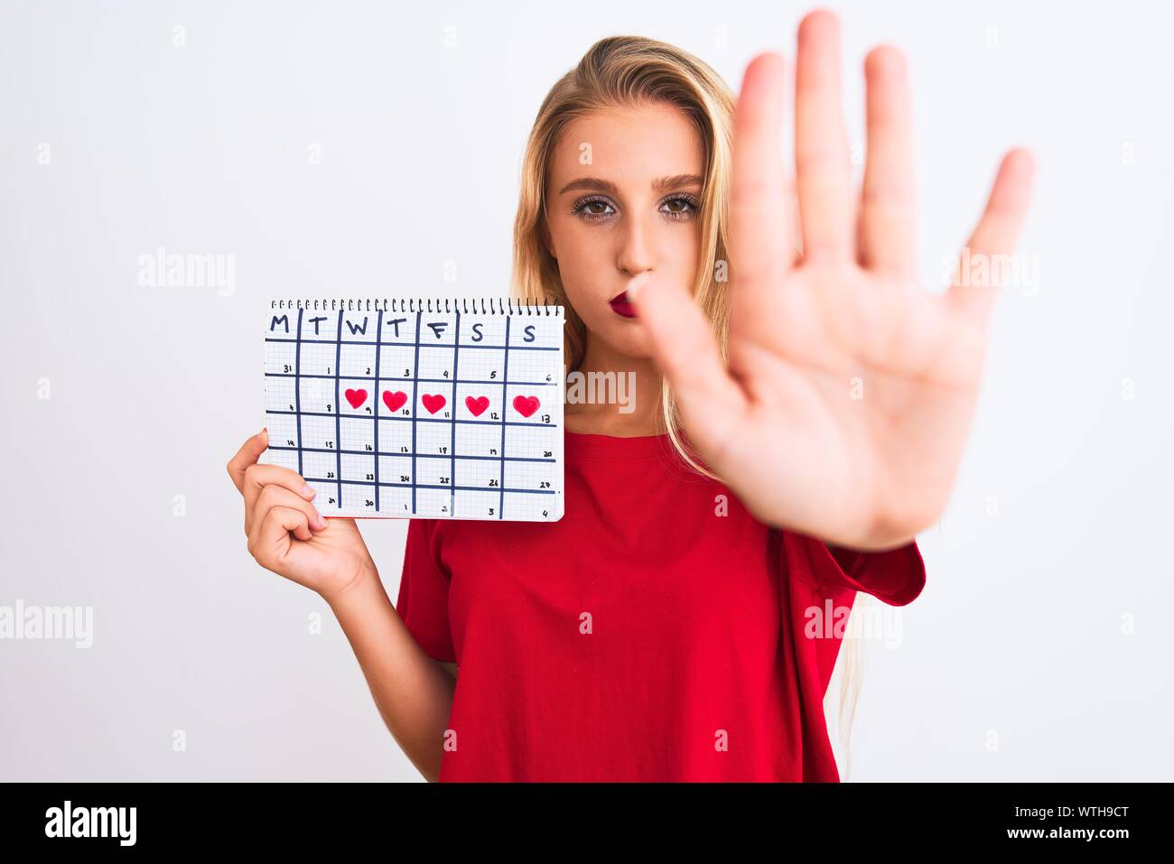 Young beautiful woman holding period calendar standing over isolated ...