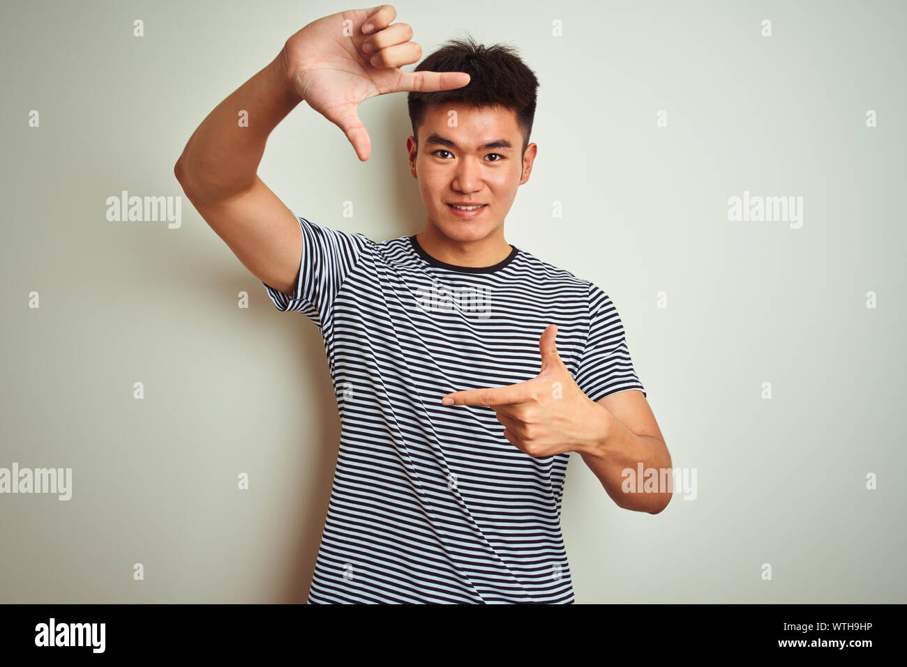 Young asian chinese man wearing striped t-shirt standing over isolated ...