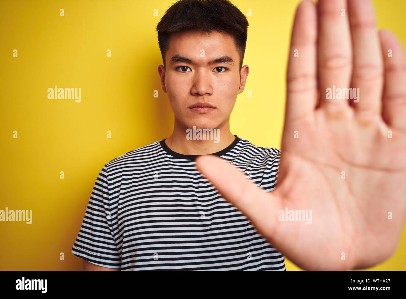 Young Asian Chinese Man Wearing Striped T Shirt Standing Over Isolated