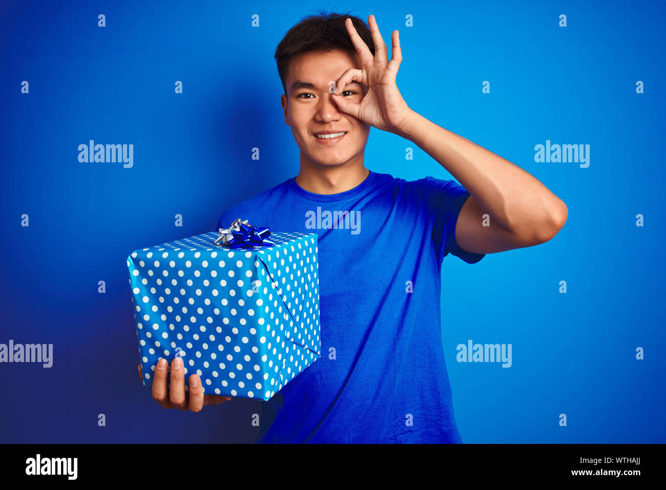 Young asian chinese man holding birthday gift standing over isolated ...