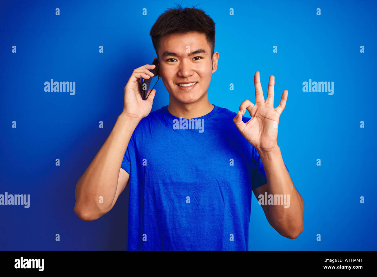 Young asian chinese man talking on the smartphone standing over ...