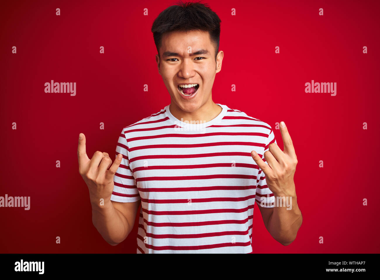 Young Asian Chinese Man Wearing Striped T Shirt Standing Over Isolated