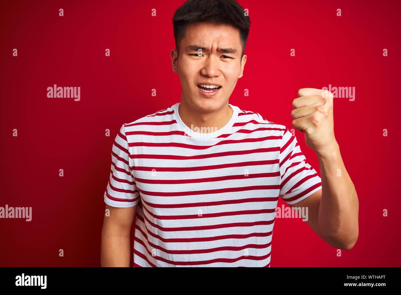 Young Asian Chinese Man Wearing Striped T Shirt Standing Over Isolated