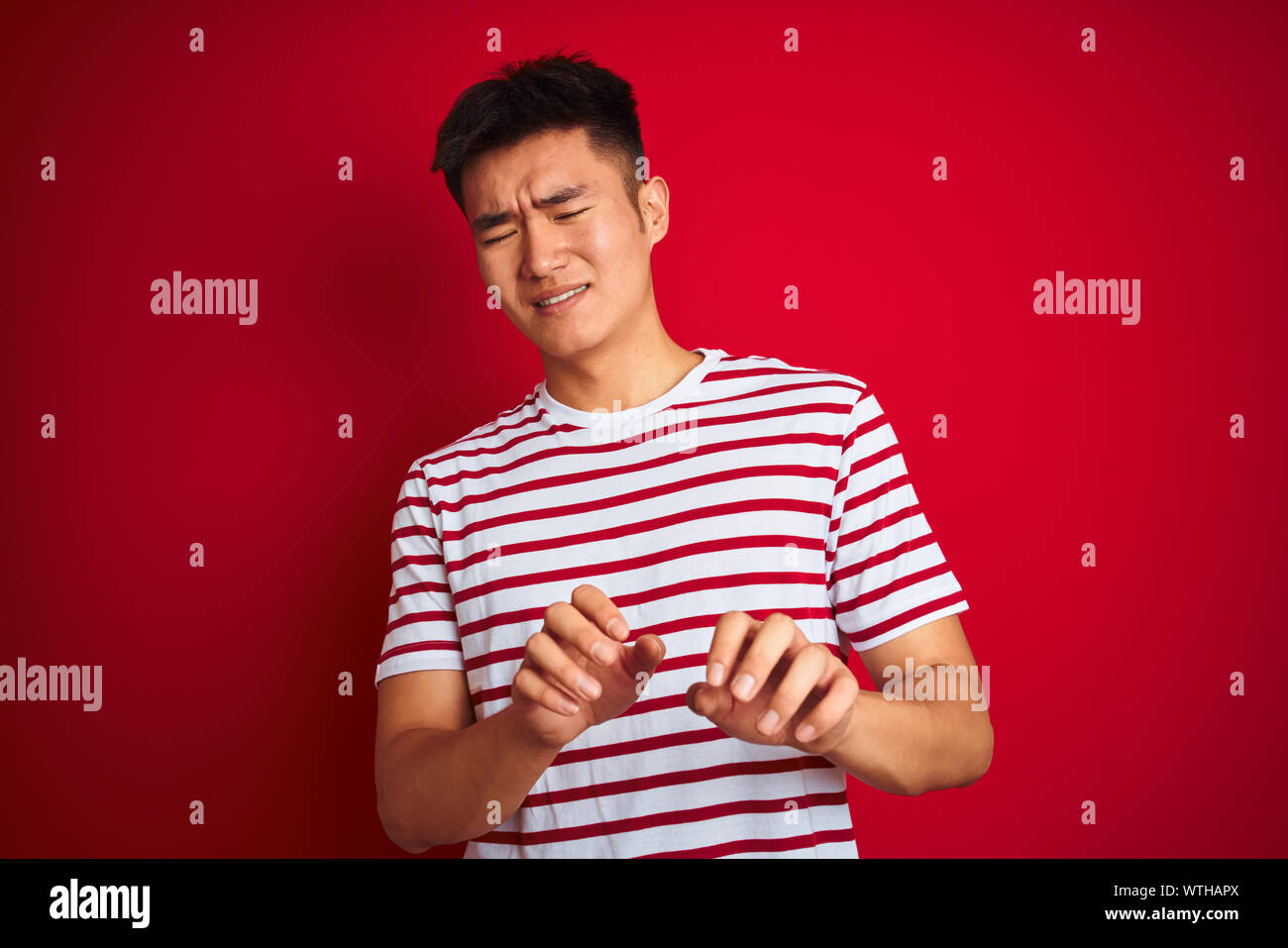 Young asian chinese man wearing striped t-shirt standing over isolated ...
