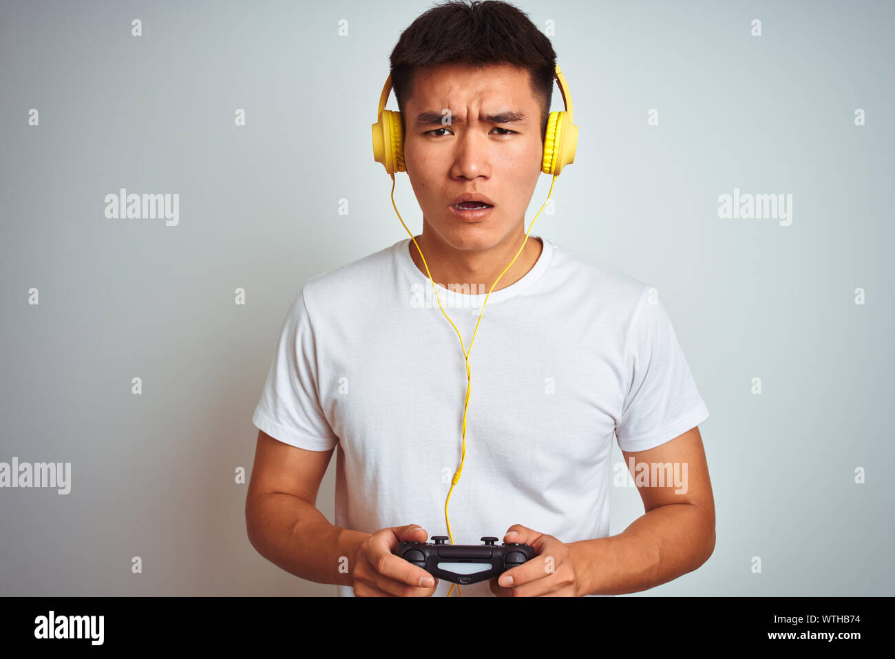 Young asian chinese gamer man playing video game standing over isolated ...