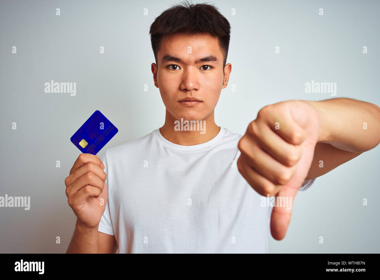Young asian chinese man holding credit card standing over isolated ...