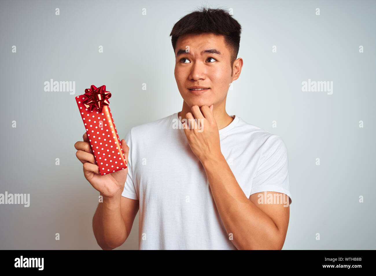 Young asian chinese man holding valentine present standing over ...