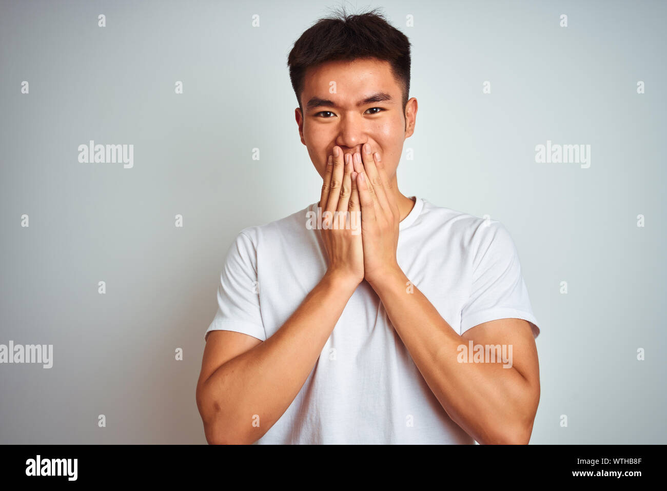 Young asian chinese man wearing t-shirt standing over isolated white ...