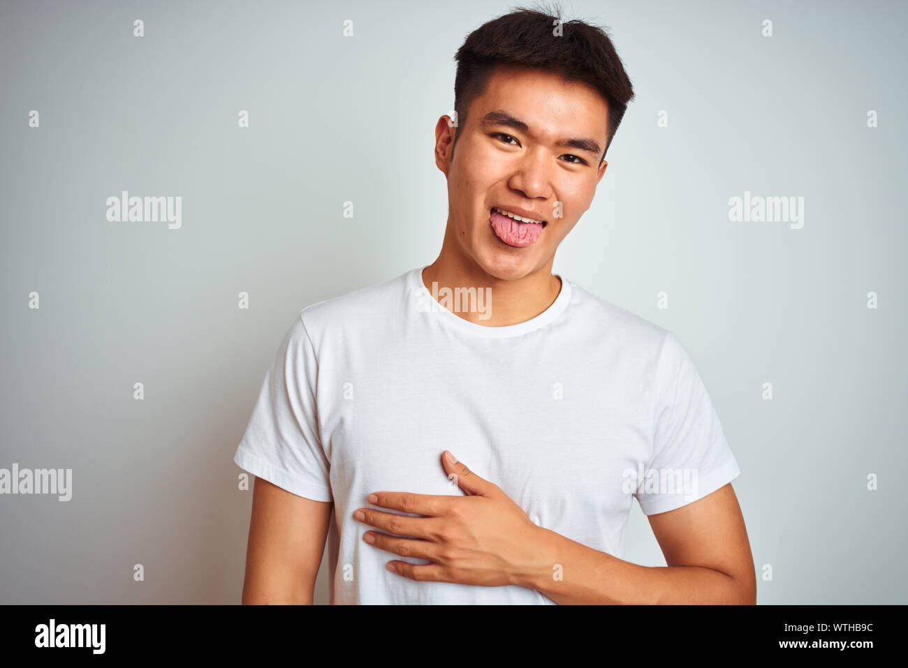Young asian chinese man wearing t-shirt standing over isolated white ...